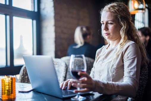 Wanita Pirang Cantik Minum Anggur Merah Dan Bekerja Di Laptop Di