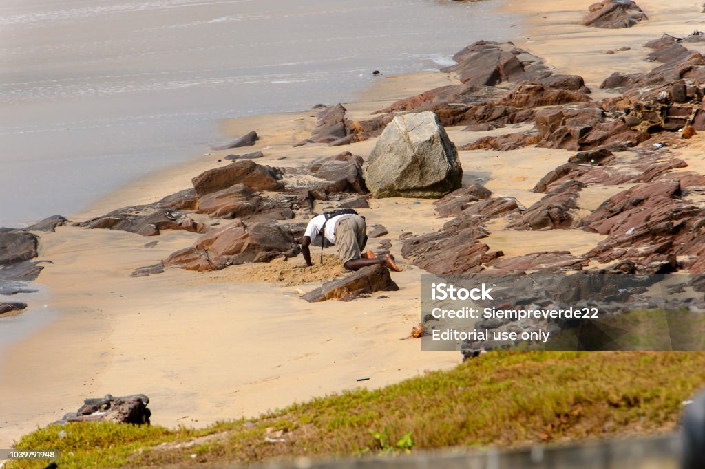 Pria Ghana Tak Dikenal Duduk Berlutut Dan Menggali Lubang Di Pantai ... Pria Ghana Tak Dikenal Duduk Berlutut Dan Menggali Lubang Di Pantai ...