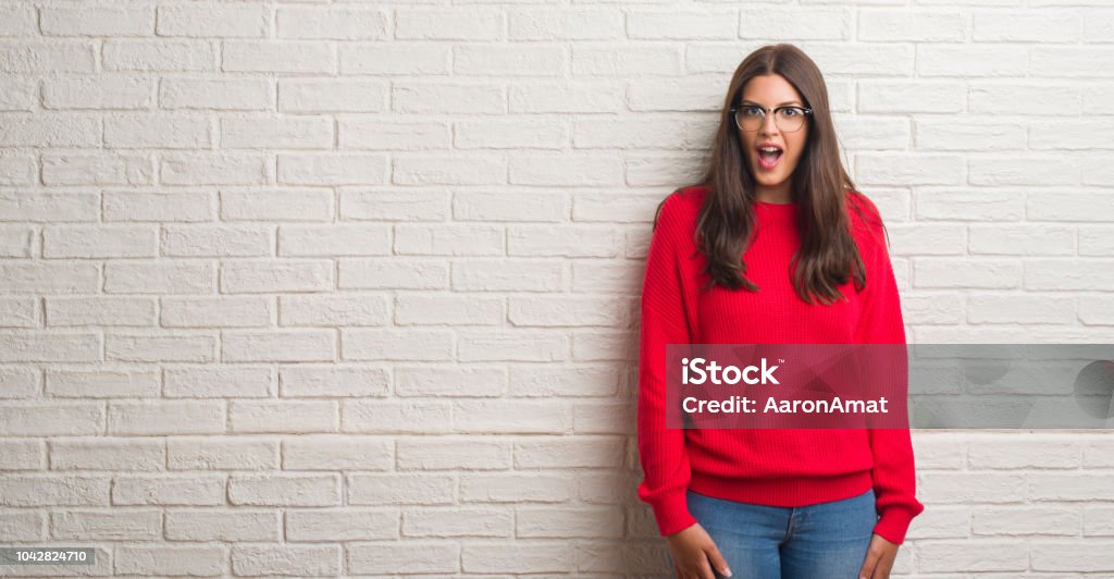 Young Brunette Woman Standing Over White Brick Wall Afraid And Shocked