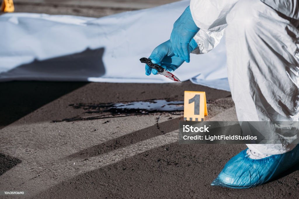 Partial View Of Criminologist In Latex Gloves And Protective Suit