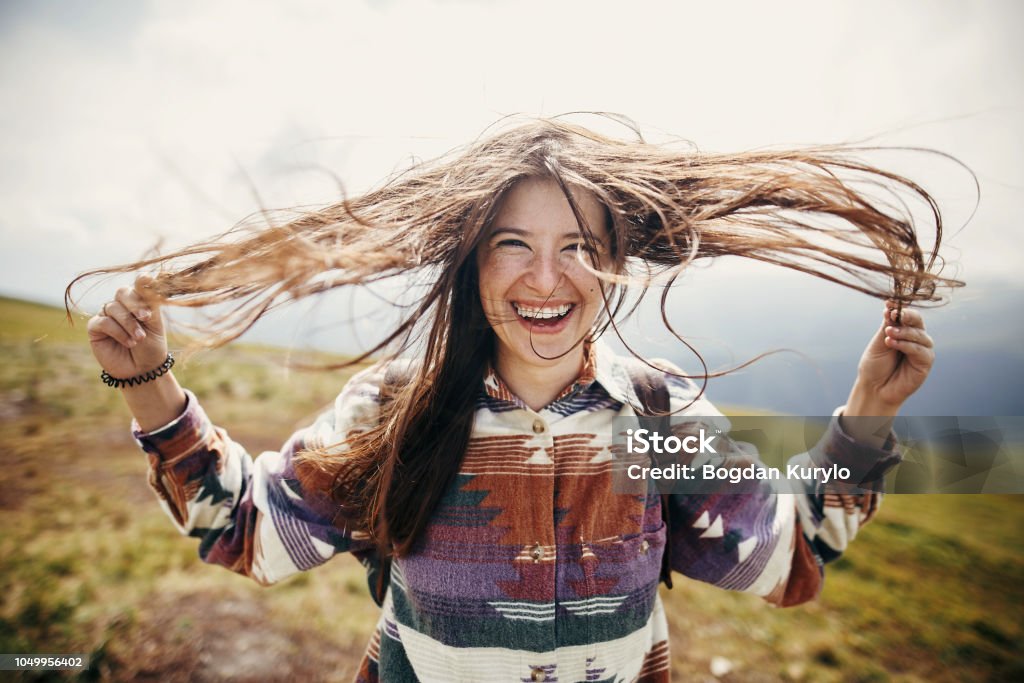 Happy Traveler Hipster Girl With Windy Hair And Smiling Standing On Top