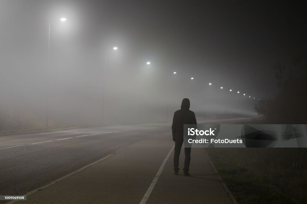 Young Man Alone Slowly Walking Under White Street Lights In Night Dark ... Young Man Alone Slowly Walking Under White Street Lights In Night Dark ...