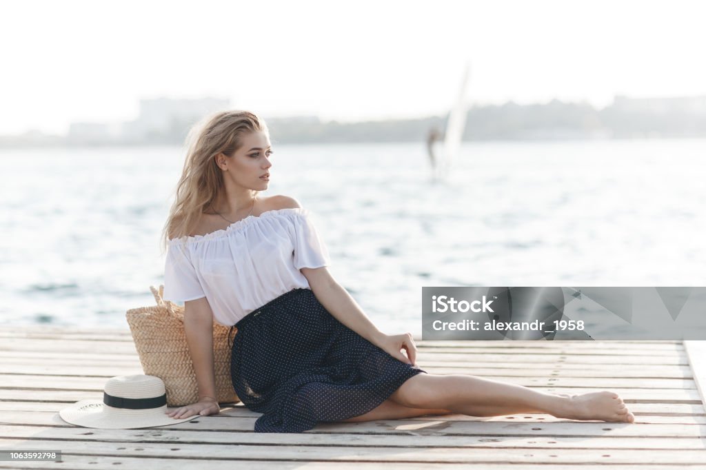 Portrait Of A Cute Girl Outdoors In Sitting On A Pier In The Spring