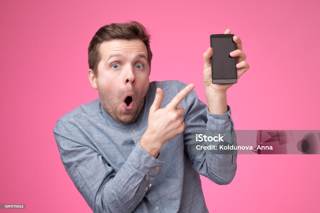Handsome Young Man Holding Smartphone Showing Gadget To Camera Isolated