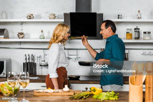 Pandangan Samping Suami Dewasa Memberi Makan Istri Di Dapur Gelas