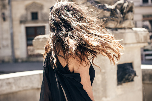 Happy Stylish Woman Waving Hair In Sunlight At Old European City Street