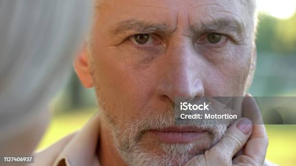 Sad Retired Man Looking Into Camera Woman Supporting Husband Closeup