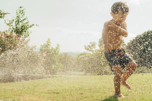 Free Stock Photo of Young Boy Running Through a Sprinkle of Water ...