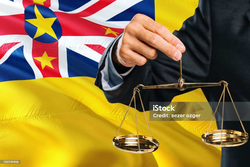 Judge Is Holding Golden Scales Of Justice With Niue Waving Flag