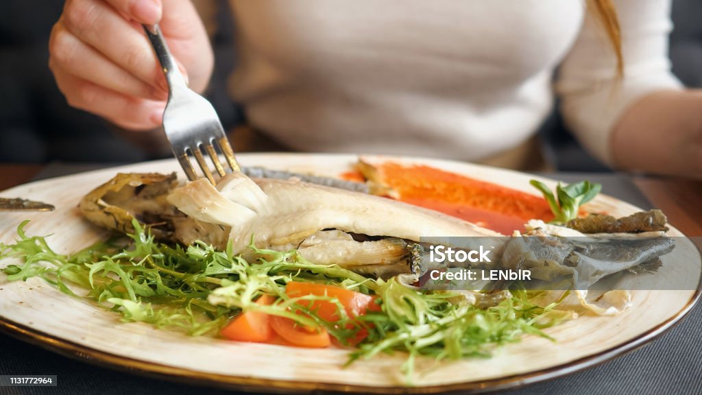 Close Up Of Unrecognizable Woman Eating Fish Steak With Knife And Fork ... Close Up Of Unrecognizable Woman Eating Fish Steak With Knife And Fork ...