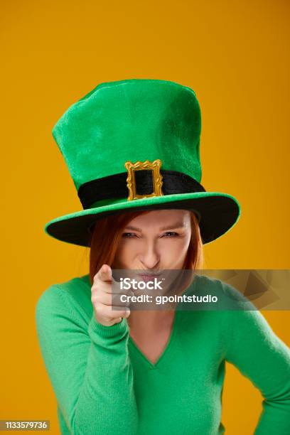Portrait Of Playful Woman With Leprechauns Hat Pointing At Camera Stock