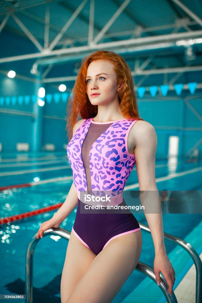 A Beautiful Redhaired Girl Stands On The Steps Of The Swimming Pool