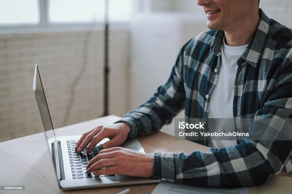 Close Up Of Positive Man Smiling While Typing On His Laptop Stock Photo ... Close Up Of Positive Man Smiling While Typing On His Laptop Stock Photo ...