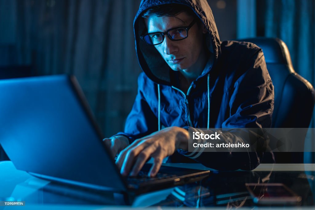 Male In The Hood Looking In The Camera Hacker Attacks And Stealing Access Databases With