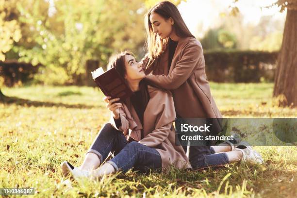 Brunette Gadis Kembar Duduk Di Rumput Dan Melihat Satu Sama Lain Salah