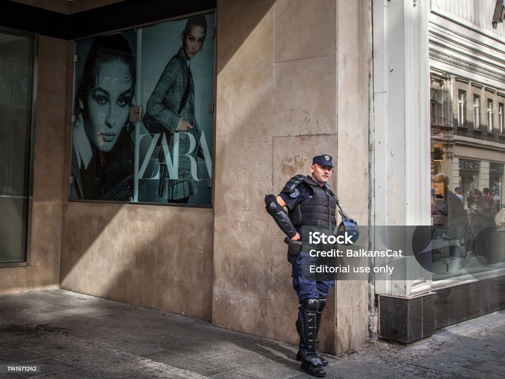 Serbian Policeman Standing In Front Of A Fashion Store With Anti Riot Gear In The Center Of