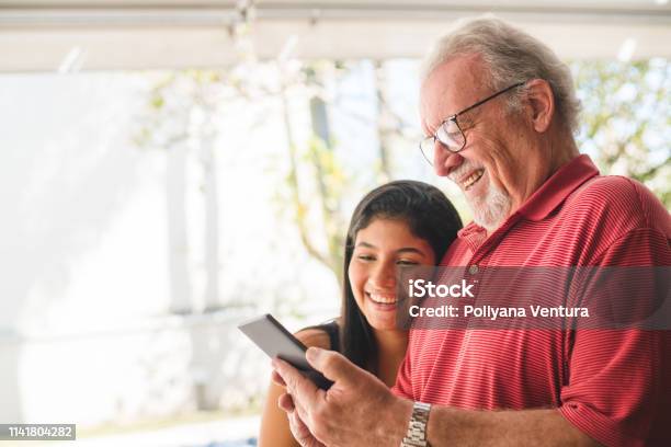 Grandpa Shows Photos On His Cell Phone For His Granddaughter Stock