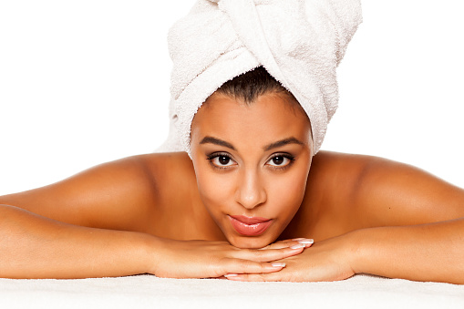 Portrait Of Young Beautiful Darkskinned Woman Lying On A White