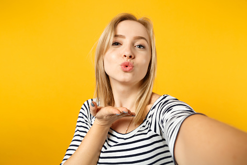 Close Up Selfie Shot Of Tender Young Woman In Striped Clothes Blowing