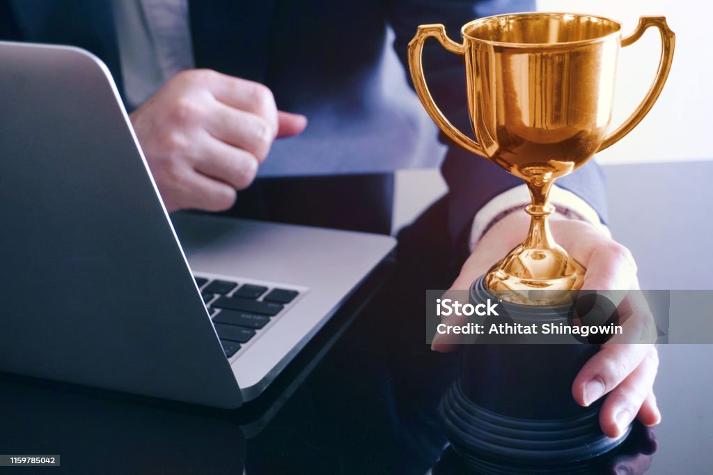 Pengusaha Memegang Piala Yang Terletak Di Atas Meja Konsep Bisnis Yang ... Pengusaha Memegang Piala Yang Terletak Di Atas Meja Konsep Bisnis Yang ...