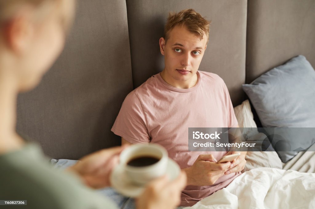 Sick Or Tired Young Man With Smartphone Looking At His Wife Stock Photo ... Sick Or Tired Young Man With Smartphone Looking At His Wife Stock Photo ...