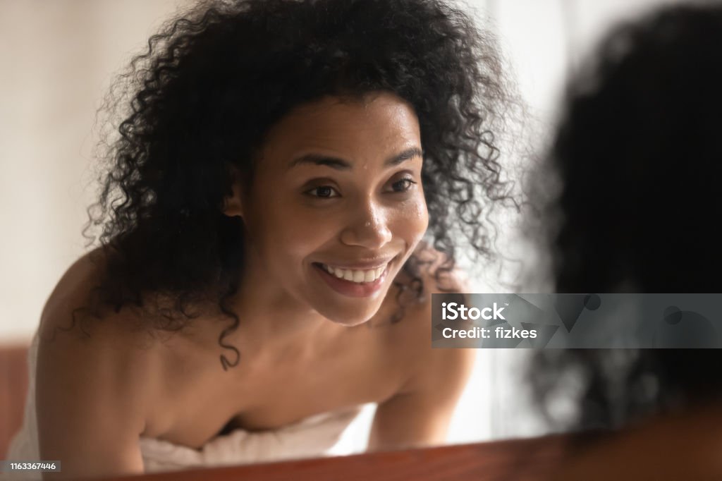 African Woman Washing Her Face In Bathroom Looking At Mirror Stock