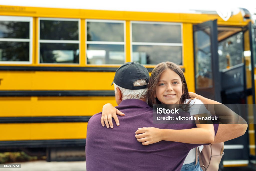 Father Meeting Daughter Coming Out Of School Bus Hugging Girl Smiling