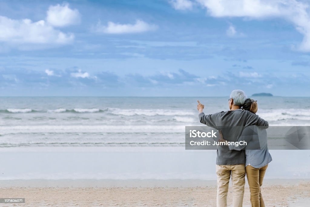 Asian Senior Couple Or Elderly People Walking And Siting At The Beach