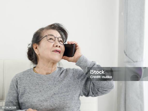 Wanita Senior Asia Membuat Panggilan Telepon Putih Duduk Di Sofa Di