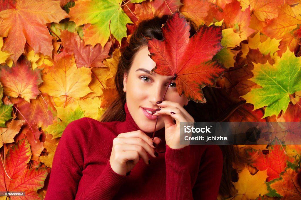 Girl Holding Red Maple Leaf In Hand Over Colorful Fallen Leaves