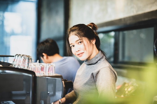 커피숍에서 바리스타에서 커피를 마시는 젊은 여성 고객 카페에서 커피를 만들기 위한 커피 머신을 사용하는 여성 바리스타 경영자에