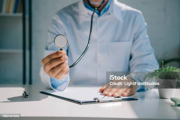 Tampilan Dokter Yang Dipotong Memegang Stetoskop Saat Duduk Di Meja ... Tampilan Dokter Yang Dipotong Memegang Stetoskop Saat Duduk Di Meja ...
