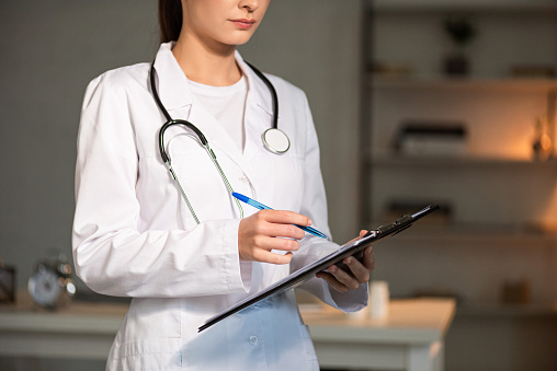 Tampilan Dipotong Dokter Dalam Tulisan Mantel Putih Di Clipboard Selama ... Tampilan Dipotong Dokter Dalam Tulisan Mantel Putih Di Clipboard Selama ...