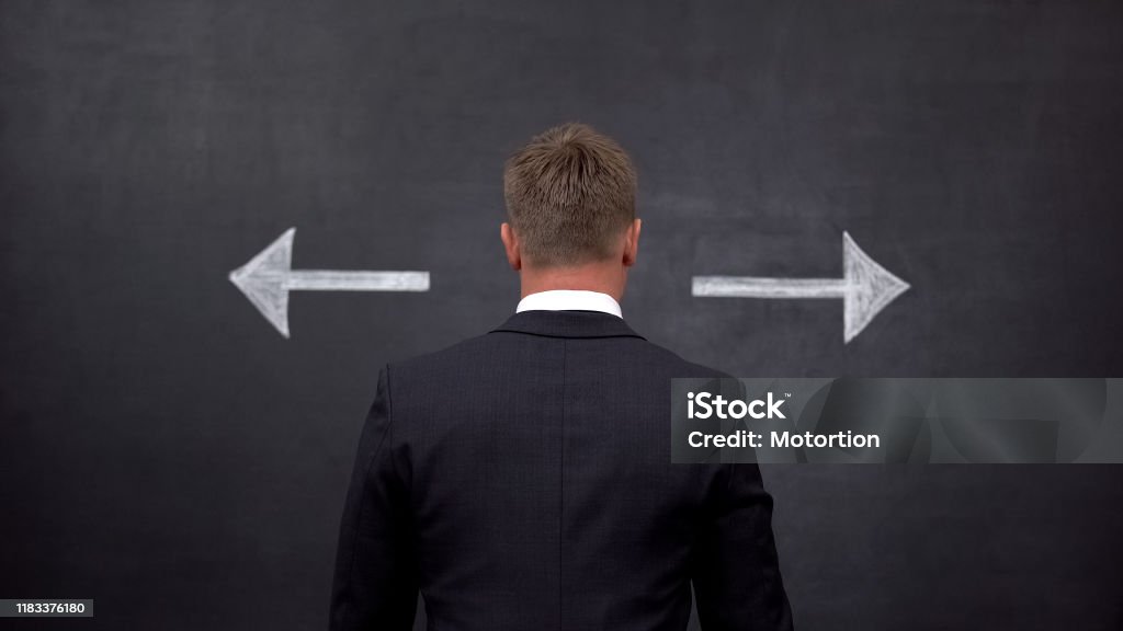 Businessman Standing Between Arrows Showing Different Directions Back