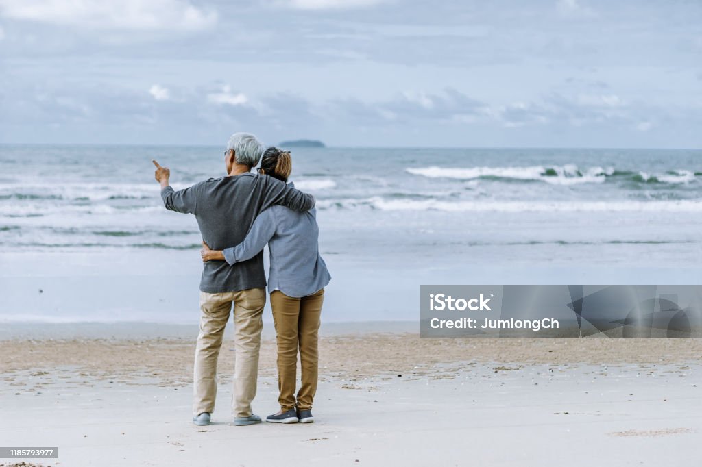 Asian Senior Couple Or Elderly People Walking And Siting At The Beach