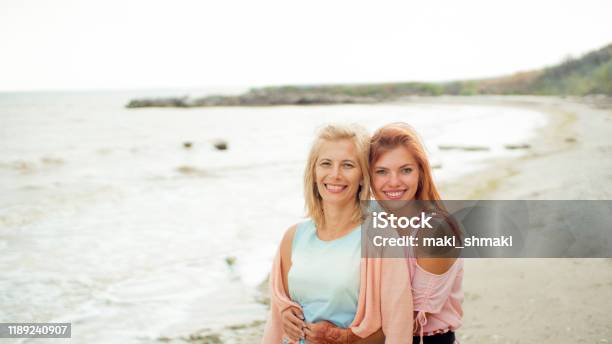 Adult Daughter Hugs Mom On The Sea Shore And Both Are Smiling Stock