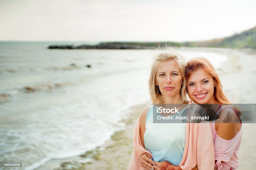 Adult Daughter Hugs Mom On The Sea Shore And Both Are Smiling Stock