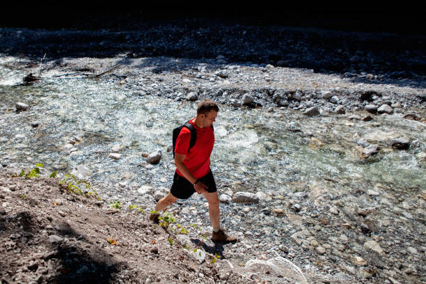 Free Stock Photo of Man Walking Across River Next to Mountain ...