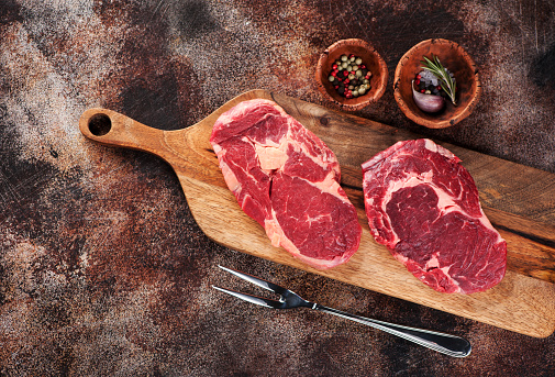 Dua Steak Ribeye Mentah Di Talenan Bawang Putih Rosemary Dan Merica