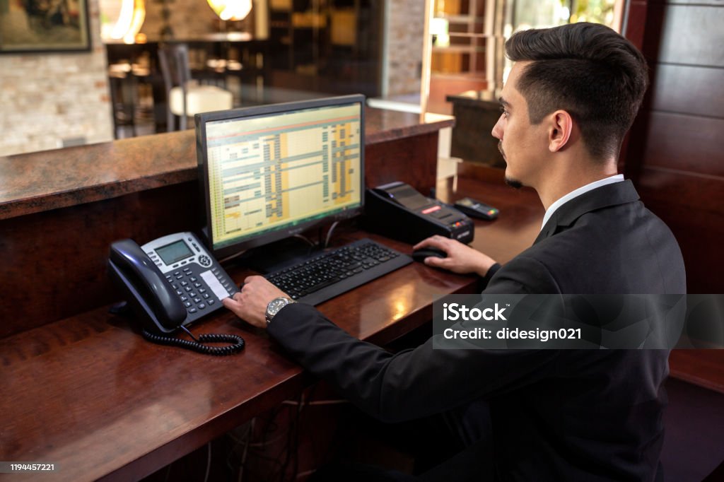 Receptionist Sitting Behind A Front Desk Stock Photo - Download Image
