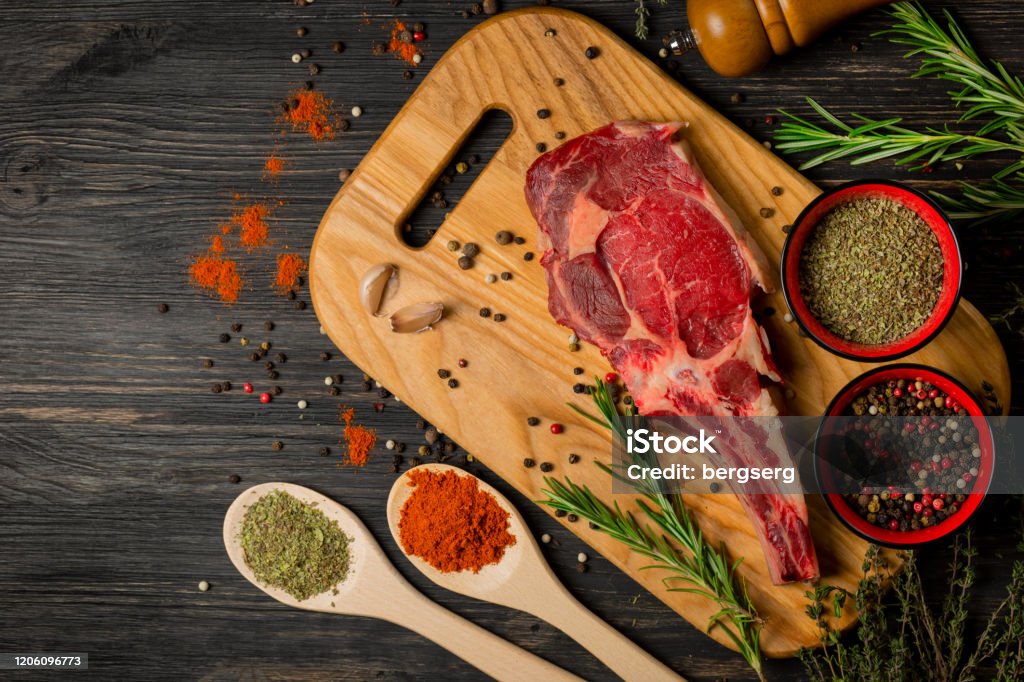 Steak Daging Sapi Mentah Di Atas Meja Kayu Gelap Dengan Bumbu Dan