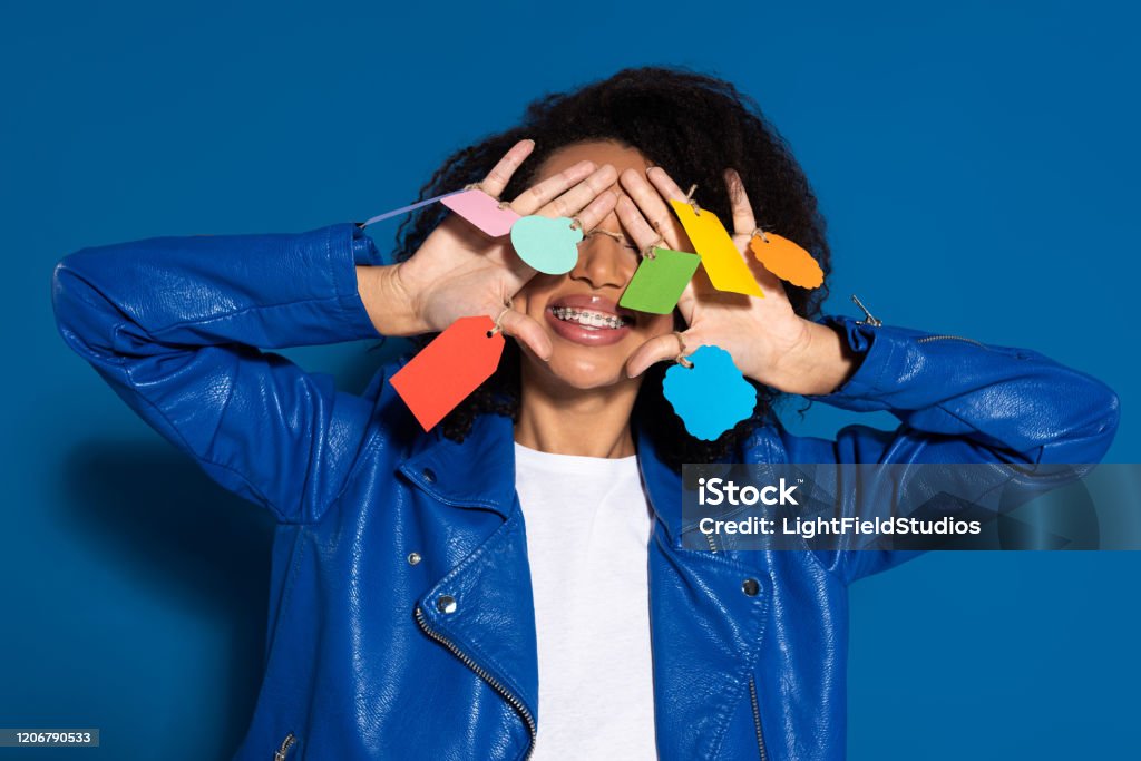 Smiling African American Woman Covering Eyes With Empty Labels On Hands