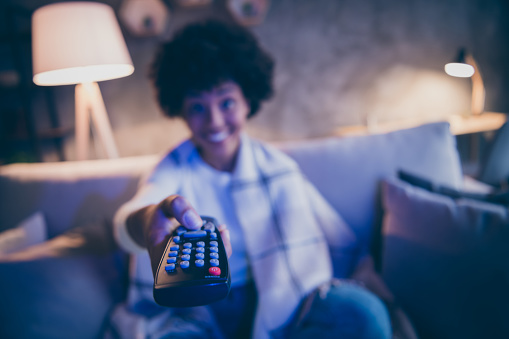 Blurred Photo Of Positive Cheerful Afro American Girl Sit Divan Watch