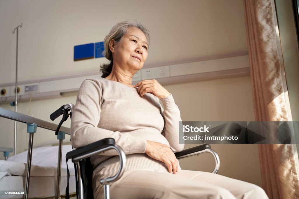Demoralized Asian Old Woman Sitting In Wheel Chair In Hospital Ward