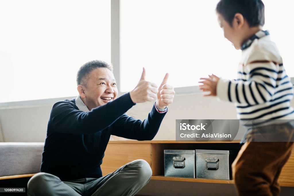 Glad Asiatisk Farfar Sitter På Golvet I Vardagsrummet Ger En Två Tummen