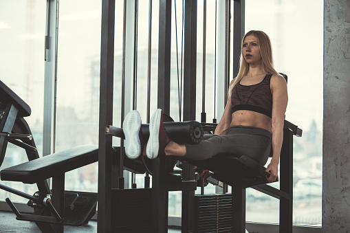 Full Length Of Female Athlete Exhaling While Doing Seated Leg Curls