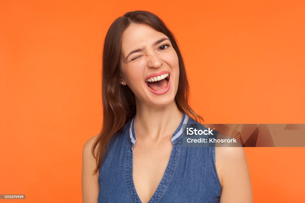 Coquettish Happy Brunette Woman In Denim Outfit Winking Playfully At