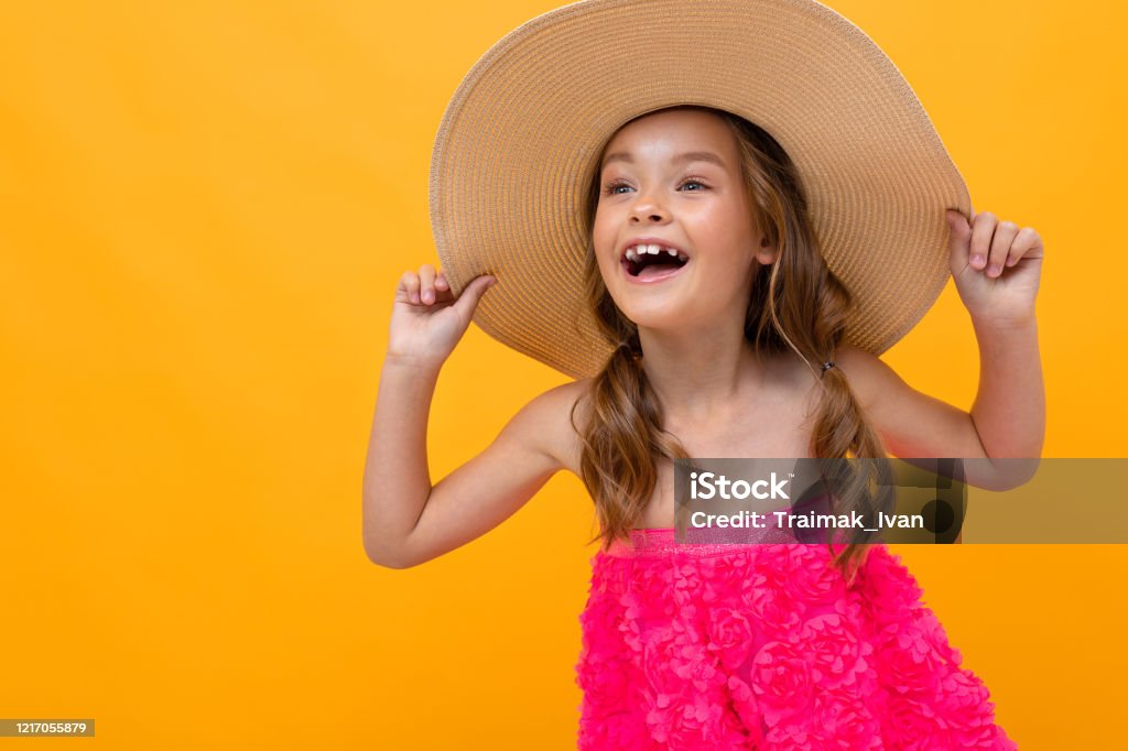 Naughty Cheerful Girl In A Pink Dress And A Straw Hat On A Background
