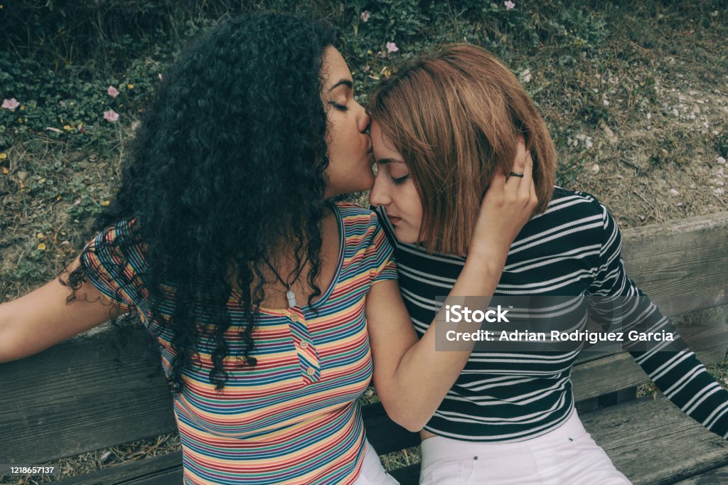 Dua Lesbian Pasangan Dari Berbeda Rasial Etnis Ciuman Di Bangku Foto