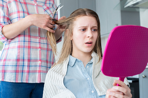 Mother Cutting Unhappy Teenage Daughters Hair At Home During Lockdown